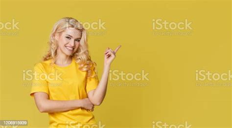 젊은 행복한 여자는 손을 보여주고 그의 손을 옆으로 펼신다 위의 노란색 배경에 텍스트와 비문에 대 한 빈 장소입니다 가리키기에 대한 스톡 사진 및 기타 이미지 Istock