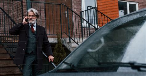 회색 머리와 수염을 가진 세련된 노인은 차 근처 거리에서 야외에서 전화로 대화를 나눕니다 사진 Unsplash의 우크라이나 이미지