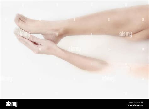 Woman Relaxing In A Hot Soapy Bath Using A Pumice Stone To Exfoliate Her Feet And Remove Dead