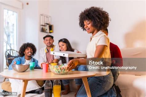 소파에 앉아 피자를 먹고 홈 파티에서 청량 음료를 마시는 다민족 친구들 청년이 거리에서 피자를 가지고 도착합니다 20 24세에 대한 스톡 사진 및 기타 이미지 Istock