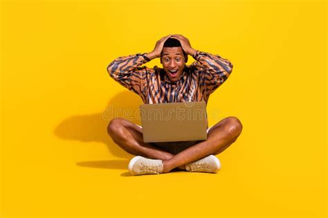 Восторженный молодой человек сидел с ноутбуком на жёлтом фоне показывая восторженную реакцию с