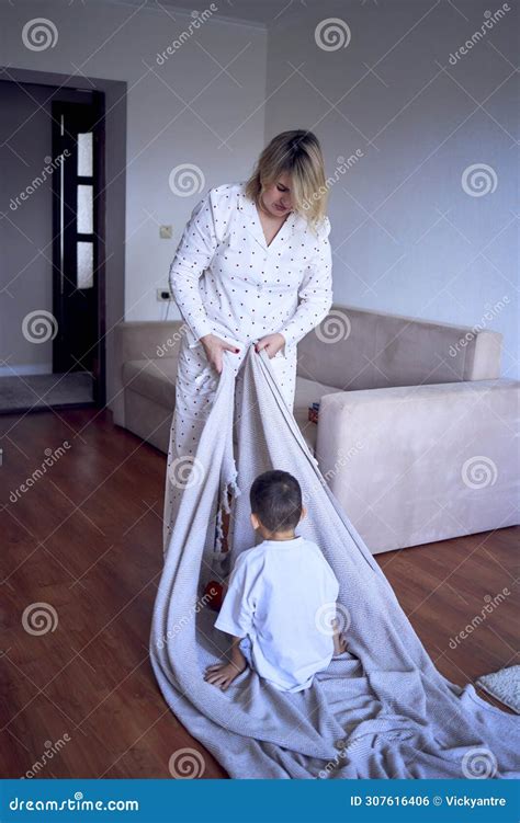 A Mother Plays And Drags Her Little Son On A Sheet Around The Room