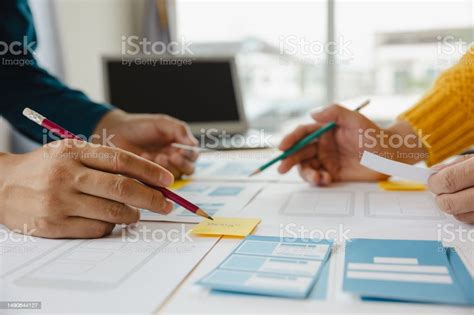 Ux 개발자와 Ui 디자이너가 현대 사무실에서 고객 요약 및 색상 코드와 함께 테이블에 모바일 앱 인터페이스 와이어프레임 디자인에 대해 브레인스토밍합니다 크리에이티브 디지털