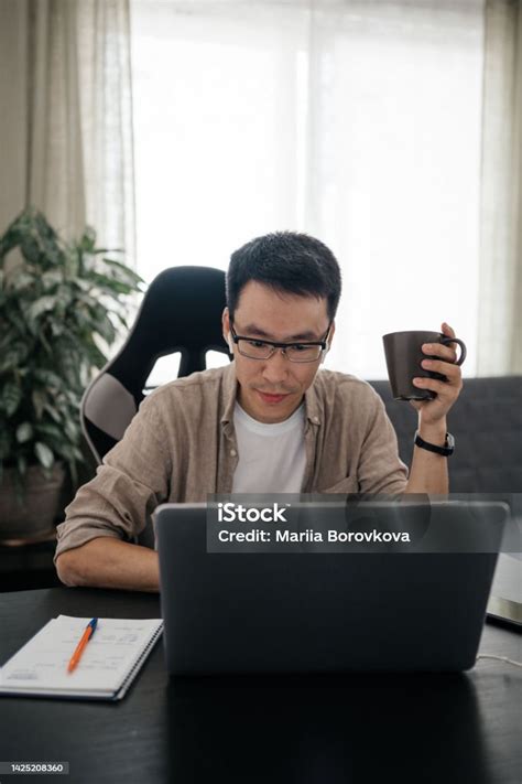 집에서 노트북을 사용하여 테이블에 앉아있는 안경을 착용 한 성인 아시아 남자 원격 작업 프리랜서 작업 개념 컵에서 마시기 30 34세에 대한 스톡 사진 및 기타 이미지