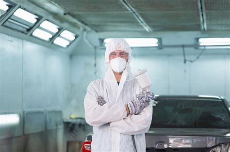 챔버에 있는 기계공 페인팅 자동차 스프레이 건과 에어 브러시를 사용하고 자동차를 칠하는 작업자 차고 페인팅 자동차 서비스 수리