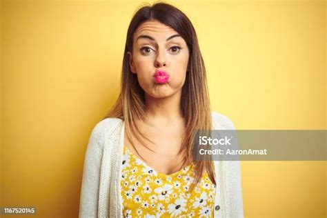 재미 있는 얼굴과 노란색 고립 된 배경 퍼핑 뺨 위에 서 재킷을 입고 젊은 아름다운 여자 공기 미친 표정으로 입이 팽창 볼에 대한 스톡 사진 및 기타 이미지 Istock