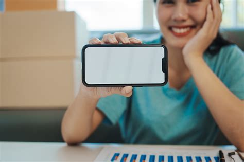 모형을 위한 빈 흰색 모바일 화면을 보여주는 손 Sme 패키지 상자를 들고 있는 아시아 여성 스마트폰을 사용하여 온라인 이메일 주문 채팅 상자 메시지 Sme 판매자를 받는