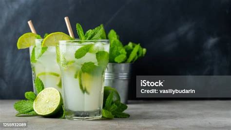 라임 민트 얼음 조각을 곁들인 수제 레모네이드 또는 모히토 칵테일 2개가 어두운 석조 테이블에 유리를 달고 있습니다 신선한 여름 음료 복사 공간을 가지고 있습니다 감귤류