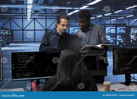 Diverse Team Of Engineers In Data Center Looking For Firewall Misconfigurations Stock Image