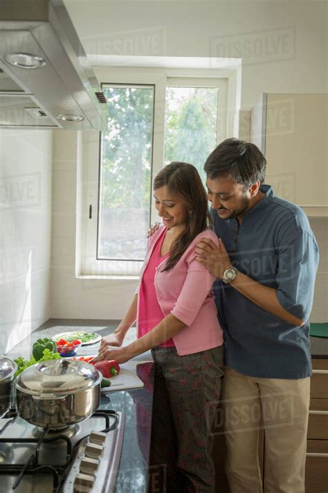 Man Standing Behind Woman In Kitchen While She Cooks Royalty Free