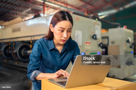 안전 헬멧과 조끼를 입은 아시아 및 아프리카 여성이 클립보드를 들고 자동차 부품 창고의 종이에 주의를 기울여야 합니다 제품 및 골판지 종이의 제조 및 처리를위한 공장 공장