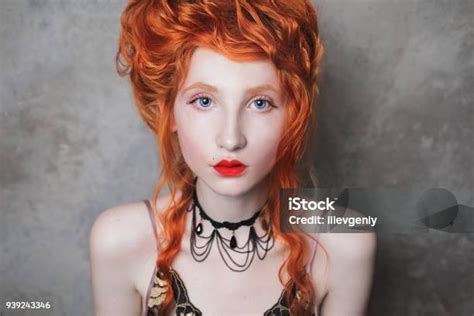 한 잠 옷에 붉은 머리를 가진 여자입니다 창백한 피부와 회색 벽의 배경에서 그녀의 목 초커와 밝은 특이 한 외관을 가진 파란 눈