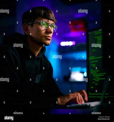Low Key Lighting Shot Of Male Computer Hacker Sitting In Front Of Screens Breaching Cyber