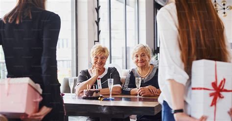 어린 소녀들은 선물 상자를 뒤에 들고 있습니다 실내에서 생일을 축하하는 가족과 친구들과 함께 있는 노인 여성 사진 Unsplash의 공생 이미지