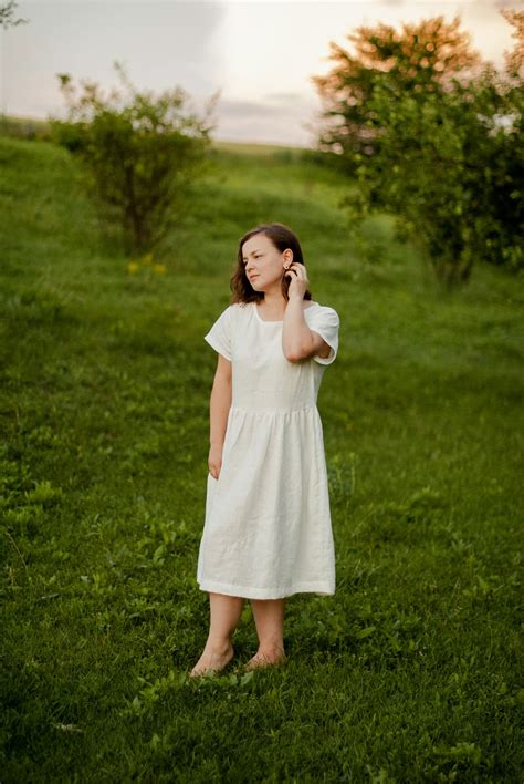낮 동안 푸른 잔디밭에 서 있는 하얀 드레스를 입은 소녀 사진 Unsplash의 무료 녹색 이미지
