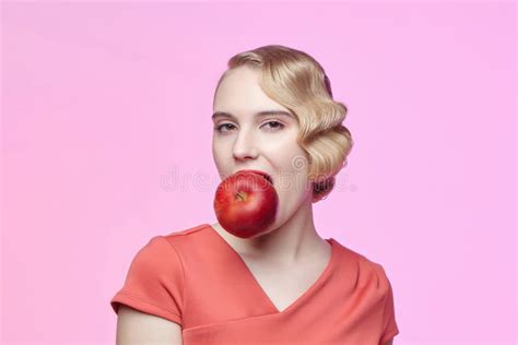 An Attractive Young Blonde With A Retro Hairstyle Holds A Red Apple In