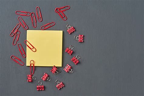 사무실 학교 또는 가정의 어두운 콘크리트 책상에 메모를 위해 빈 사각형 종이 근처에 많은 바인더와 클립을 흩어져 있습니다 텍스트의 공백입니다 맨 위 보기 개성 개념에 대한