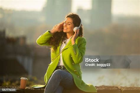 화창한 가을 날에 는 스마트 폰과 테이크 아웃 커피로 음악을 듣는 예쁜 젊은 여성 25 29세에 대한 스톡 사진 및 기타 이미지 25 29세 Brand Name
