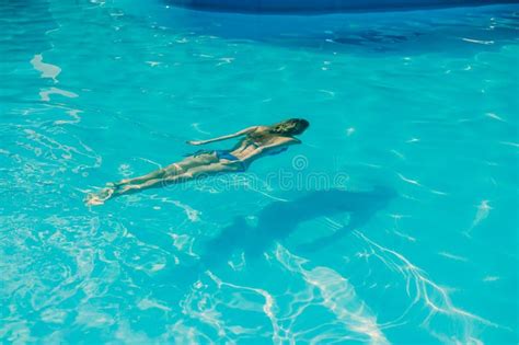 Young Slim Woman In A Black Bikini Swimsuit Swims Underwater In The