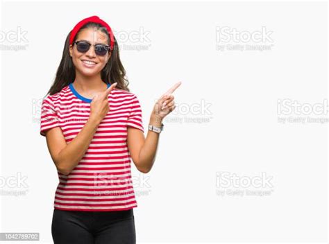 젊은 아름 다운 아랍 여자 웃 고 옆에 두 손과 손가락으로 가리키는 카메라 보고 격리 된 배경 위에 선글라스를 착용 가리키기에 대한 스톡 사진 및 기타 이미지 Istock