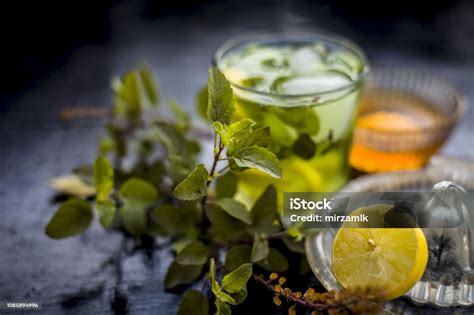 Herabal 음료 또는 원시 바 질 원시 꿀 얼음 조각 나무 표면 기침 스트레스 두통 등 치료에 도움이 됩니다에 레몬 주스와 함께 투명 한 유리에 바 질 레모네이드