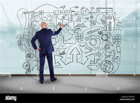 view of a businessman drawing a hand drawn complex schema on a wall