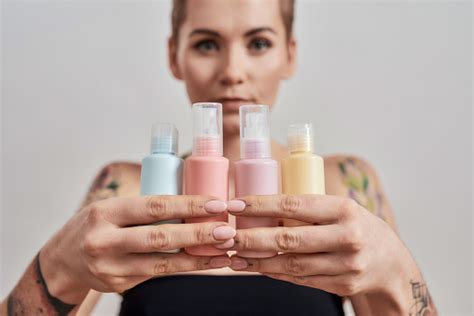 회색 배경에 고립 된 화장품 머리카락 및 스킨 케어 제품으로 플라스틱 병을 들고 있는 짧은 머리를 가진 문신을 한 여성의 초상화 개인 장식품에 대한 스톡 사진 및 기타