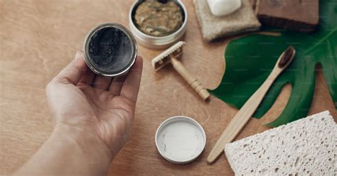 폐기물 제로 대나무 칫솔 비누 고체 샴푸 금속 면도기 녹색 몬스테라 잎이 있는 나무에 데오도란트를 배경으로 유리 병에 천연 에코 숯 치약을 들고 있습니다 사진