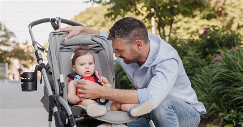유모차에 아기 딸과 함께 걷는 백인 자랑스러운 아버지 가족 아빠와 딸은 여름날 도시 거리에서 야외에서 함께 있습니다 아이들과 함께하는 도시 생활 행복한 라이프 스타일