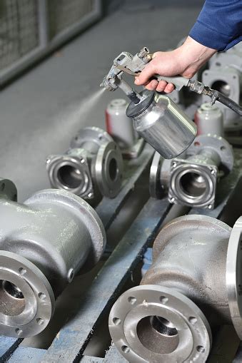 특별 한 방에서 공장에서 노동자는 스프레이 건에서 밸브의 부분을 페인트 회색 색깔 손 및 살포 총 가까이에 있는 페인트 벨 브