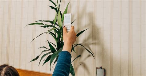 벽걸이 에어컨 앞에서 리모컨을 들고 있는 사람 사진 Unsplash의 불황 이미지