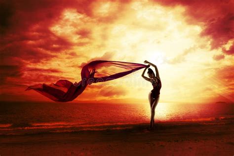 Сексуальный силуэт женщины над красным небом захода солнца чувственным женским пляжем Стоковое