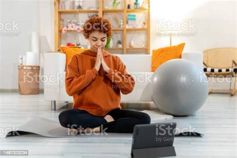 요가 마음 챙김 명상 집에서 요가를 연습하는 젊은 건강한 아프리카 소녀 연꽃에 앉아 있는 여자는 요가 매트에 눈을 감고 실내에서