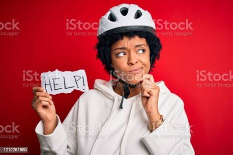 곱슬 머리를 가진 아프리카 계 미국인 여성 자전거 헬멧 을 들고 종이와 도움 메시지 심각한 얼굴 질문에 대 한 생각 매우 혼란 스러운 아이디어 개념에 대한 스톡 사진 및