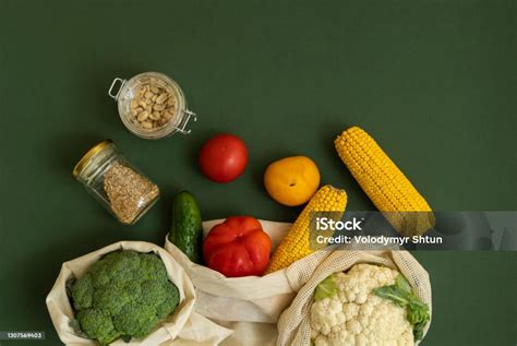 녹색 표면에 유리 항아리에 에코 가방과 견과류야채 후추 토마토 옥수수 오이 브로콜리 콜리플라워 를 재사용 가능한 쇼핑 에코