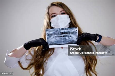 인간 치아의 X선 파노라마 사진 치과 의사는 노란색 의료용 장갑을 끼고 엑스레이 파노라마 사진을 손에 들고 있습니다 치과 의사 수술에서 치과 엑스레이 파노라마 사진 보조원에