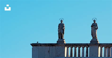 푸른 하늘을 배경으로 한 건물 위에 두 개의 동상이 있습니다 사진 Unsplash의 무료 예술 이미지