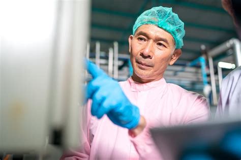 생산 라인에 과일 주스 유리가 병에 담긴 컨베이어 벨트의 음료 공장에서 일하는 작업자 프리미엄 사진