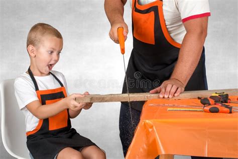Dad And Son Working Together In The Workshopsawing Wooden Planks Stock Image Image Of