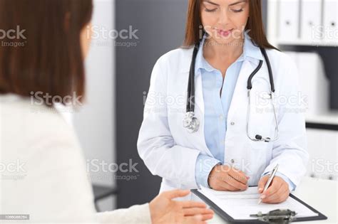 의사 그리고 환자 응급 병원에서 리셉션 데스크 근처에 서 있는 동안 뭔가 논의 병원에서 직장에서 의사입니다 의학 및 건강 관리 개념 가리키기에 대한 스톡 사진 및 기타