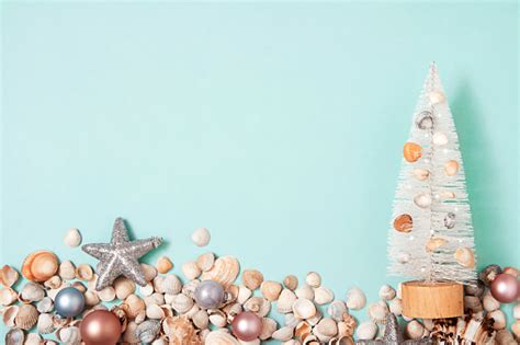 흰색 가문비 나무 나무가있는 파스텔 블루 배경에 크리스마스 공과 조개 껍질의 프레임 밝고 다채로운 미니멀 아트 구성 크리스마스와 새해의 개념 공간을 복사합니다 12월에 대한