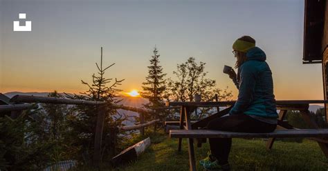 파란 거품 재킷을 입은 여자가 앉아서 일출 동안 산에 커피를 마시고 있습니다 사진 Unsplash의 무료 해돋이 이미지