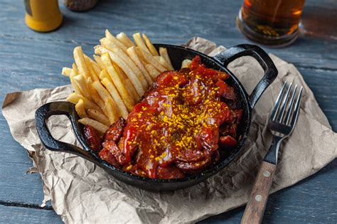 크래프트 페이퍼에 검은 팬에 감자 튀김을 곁들인 카레부르스트는 나무 테이블에 맥주를 올려 드실 수 있습니다 0명에 대한 스톡 사진 및 기타 이미지 Istock