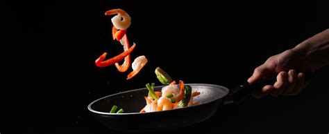 해산물 요리사가 새우를 후추 스파이크 콩 브뤼셀 콩나물을 프라이팬에 넣습니다 디자인 메뉴 레스토랑 동양 요리 건강한 음식에 대한 검은 배경에 고급 요리에 대한 스톡 사진 및