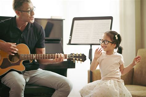 음악 수업과 재미를 여자 아이 유아의 장면 음악 교사와 사랑스러운 어린 소녀는 함께 노래를 노래하는 동안 기타를 연주 아이 뇌 개발 2명에 대한 스톡 사진 및 기타 이미지