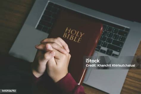 기독교인들은 아침에 하나님께 온라인으로 예배를 드리기 위해 교회의 나무 탁자 위에 성경과 노트북을 놓고 기도하기 위해 손을 접었습니다 사람은 믿음 영성 종교 개념으로