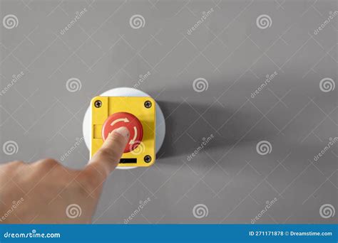 an industrial emergency stop button with a finger pressing down stock
