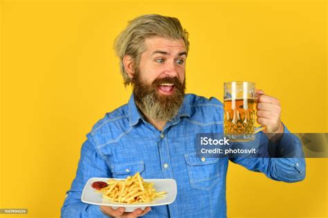 건배 Tv에서 축구를 시청합니다 미국 식 패스트 푸드 맥주와 감자 튀김을 가진 행복한 수염 난 남자 감자 튀김 미국 술집에서 맥주 잔을 마시고 감자를 먹는 남자 건강에 좋지