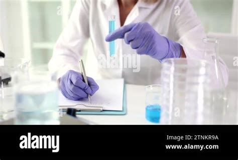 Scientist Holds Test Tube With Examined Blue Reagent Writing Down