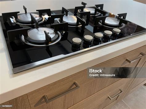 현대 부엌 5 버너 가스 호브 스토브의 클로즈업 이미지 카운터 스토리지 무승부 중앙 웍 링 흰색 돌 코리안 조리대와 검은 유리 표면 다이얼과 노브의 행 높은 전망 전경에